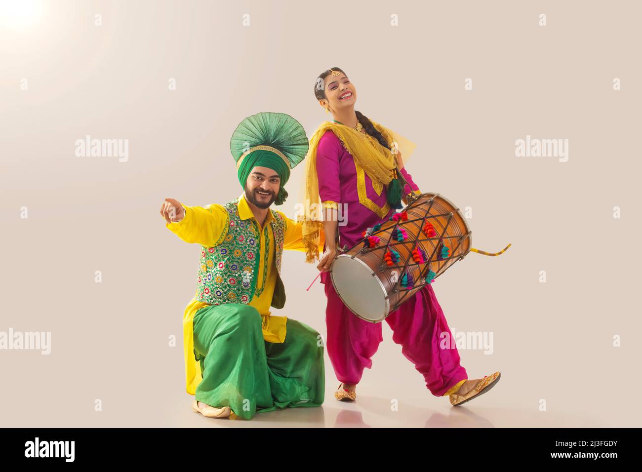 Sikh couple performing bhangra and playing drum during Baisakhi ...
