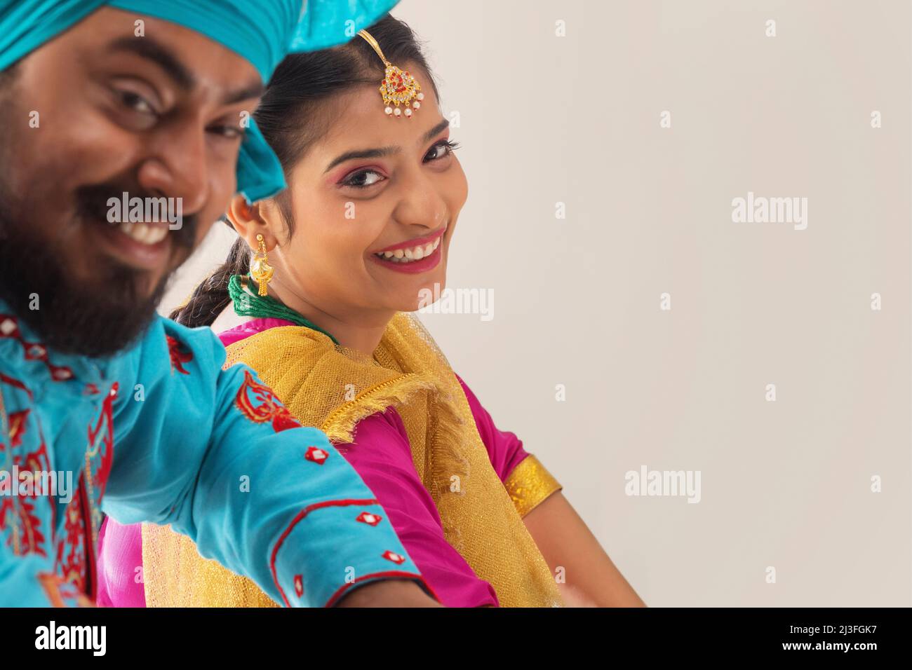 Close-up portrait of happy Sikh couple posing in front of camera during ...