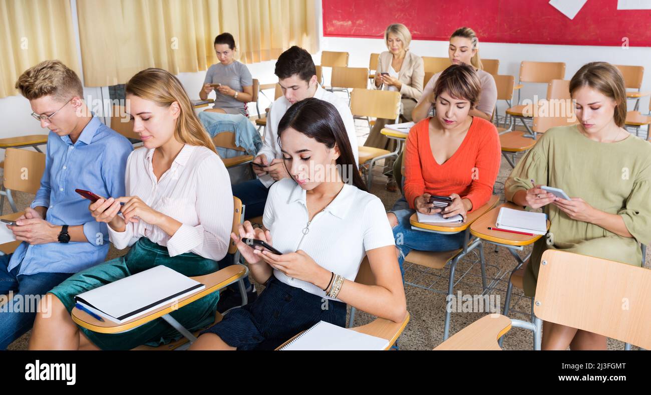 People sitting with mobile phones in classroom Stock Photo - Alamy
