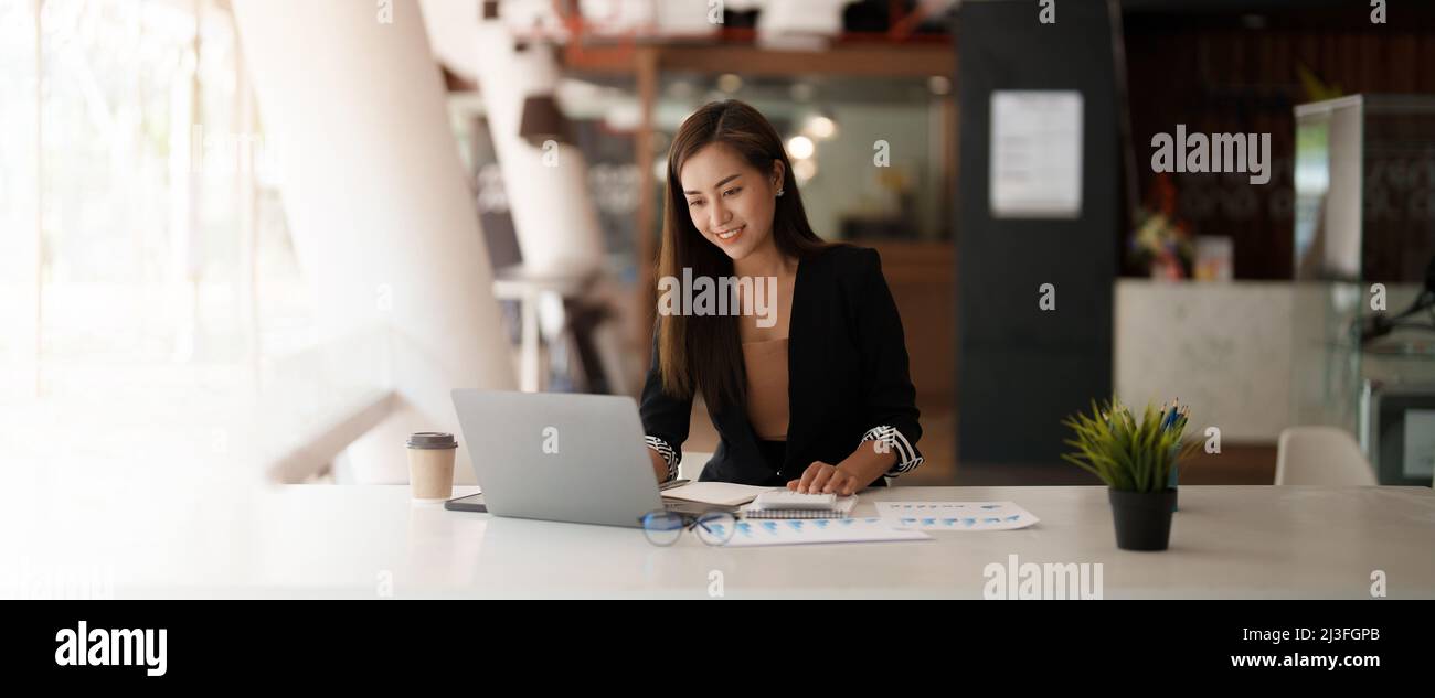Portrait asian business woman working on laptop computer and calculator ...