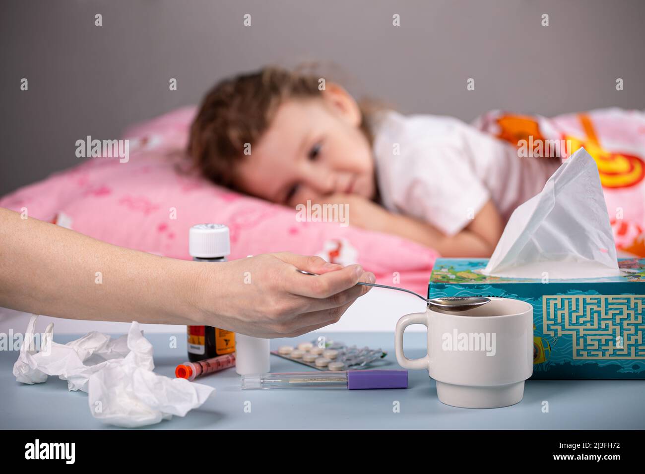 mom holds a spoon with medicine against the background of her little ...