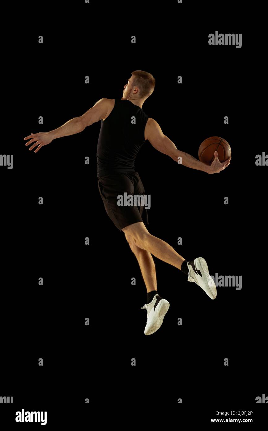 Dynamic portrait of young man, basketball player in black uniform ...