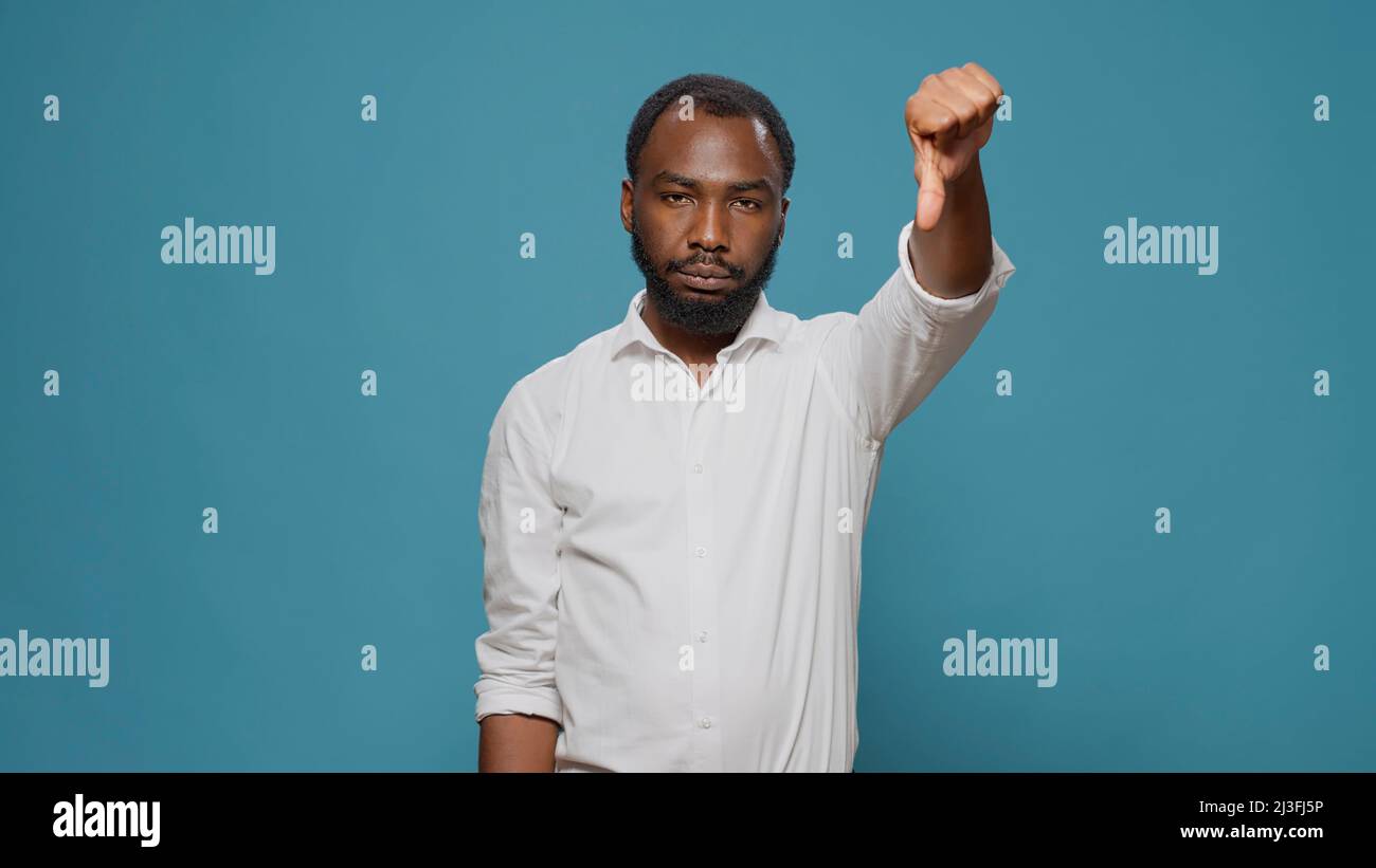 Negative person doing thumbs down gesture in studio, disagreeing with ...