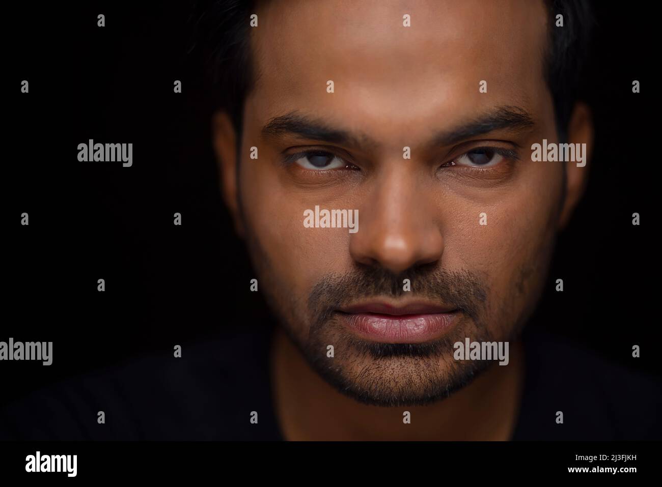 Close-up portrait of a serious young man against dark background Stock ...