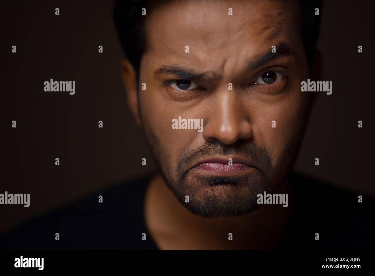 Close-up portrait of an angry young man against dark background Stock ...