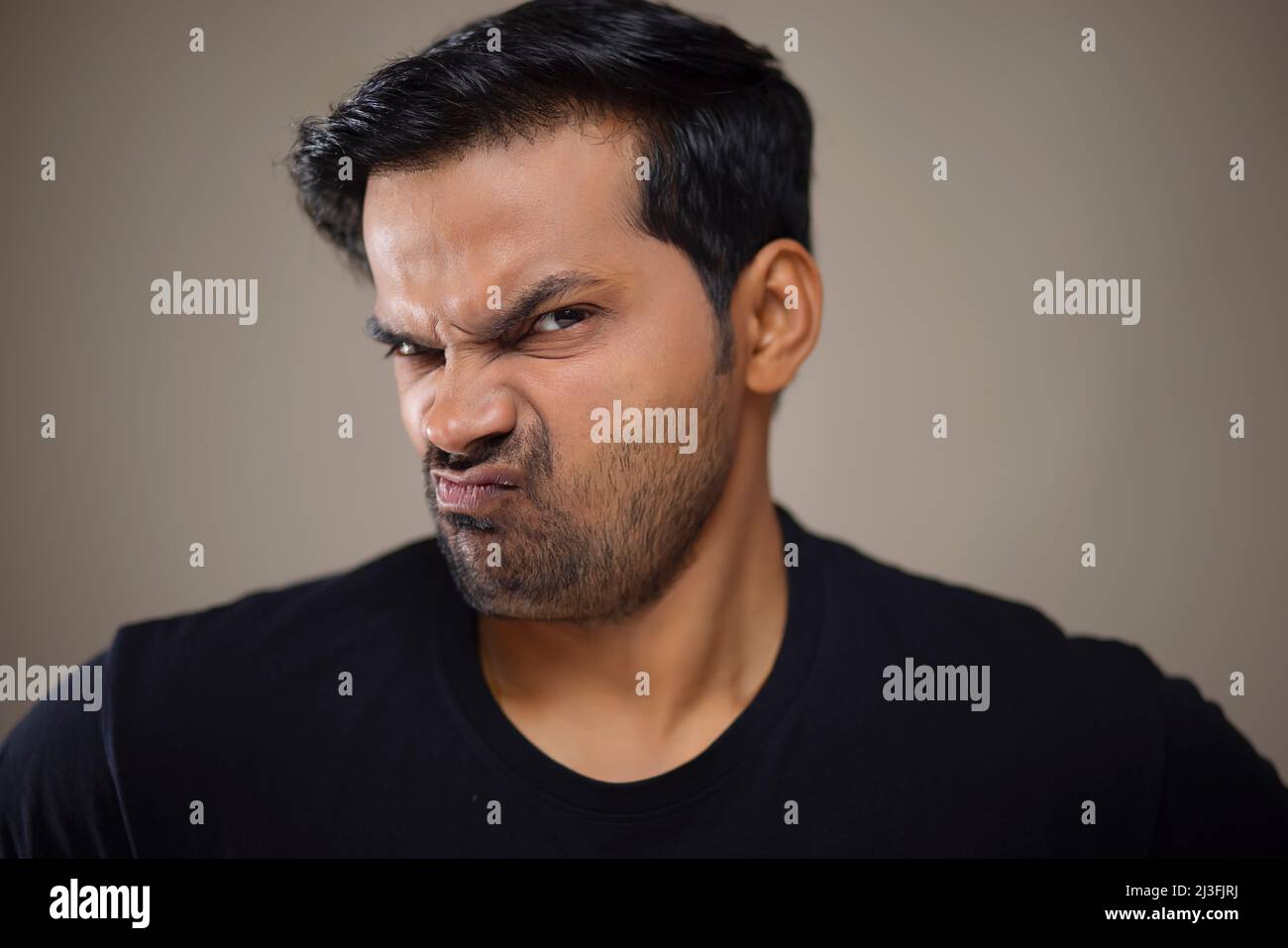 Portrait of a young man frowning angrily at the camera Stock Photo - Alamy