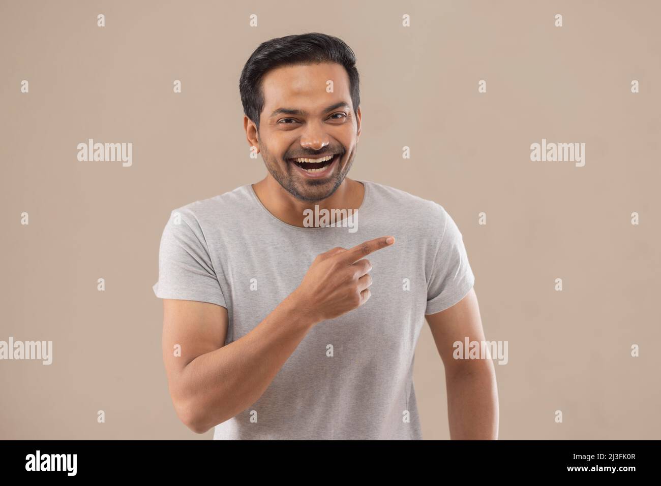 Portrait of a happy young man laughing and pointing away with his ...