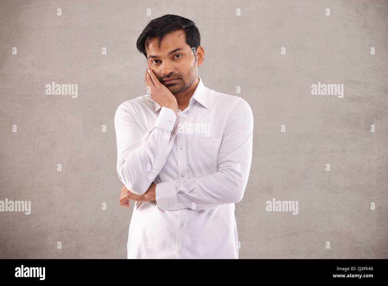 Portrait of a sad young man in white shirt looking at camera with his ...