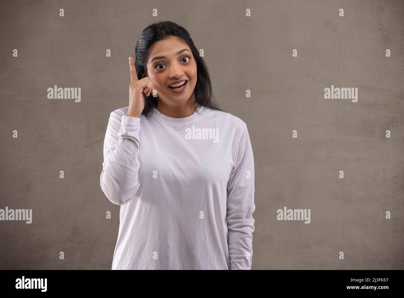 Portrait of a happy young woman pointing upwards with her finger Stock ...