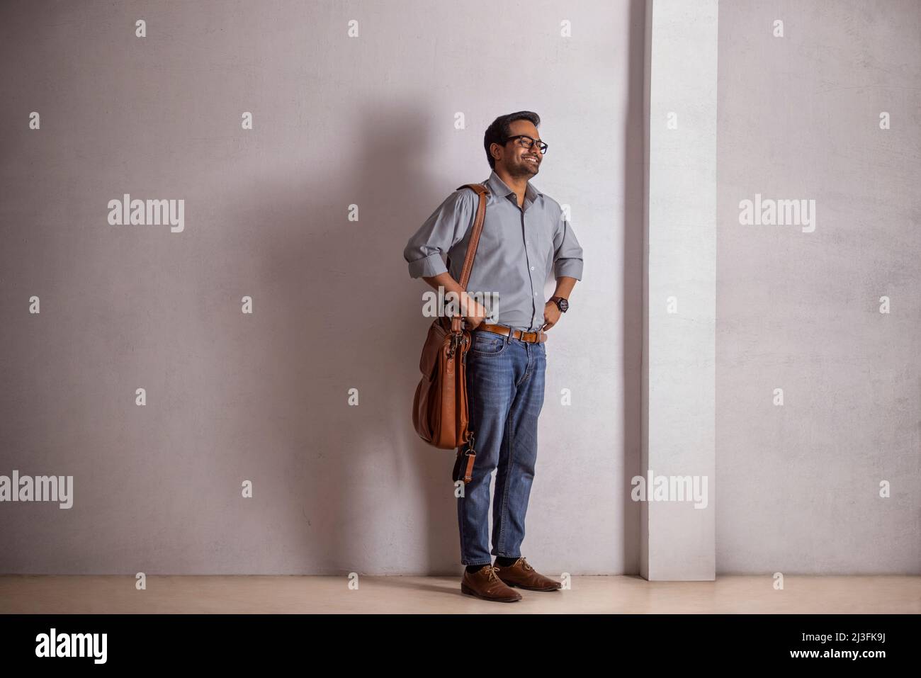 An employee with a bag on his shoulder looking elsewhere while standing ...