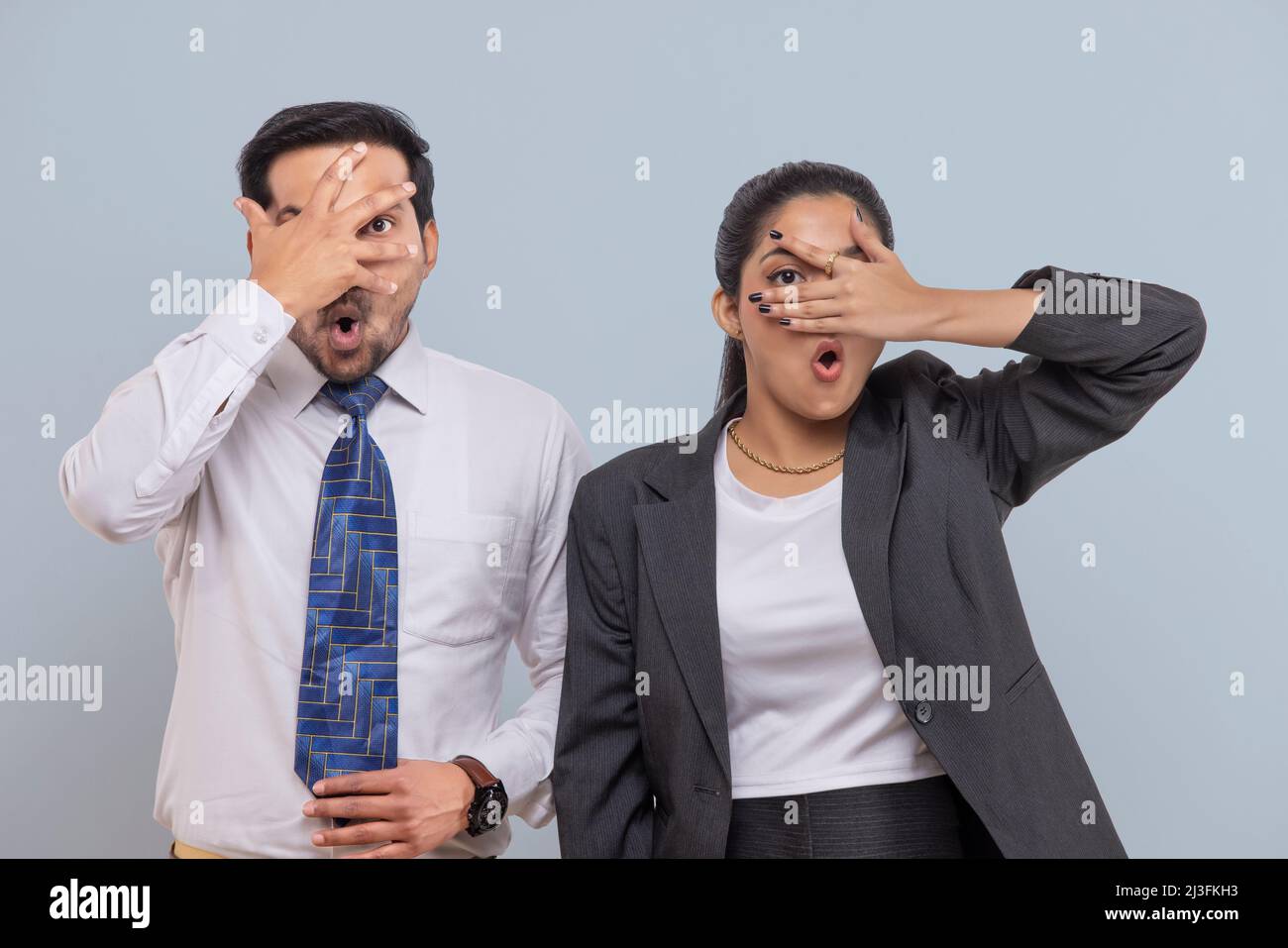 Surprised corporate couple covering face with palms and looking at ...