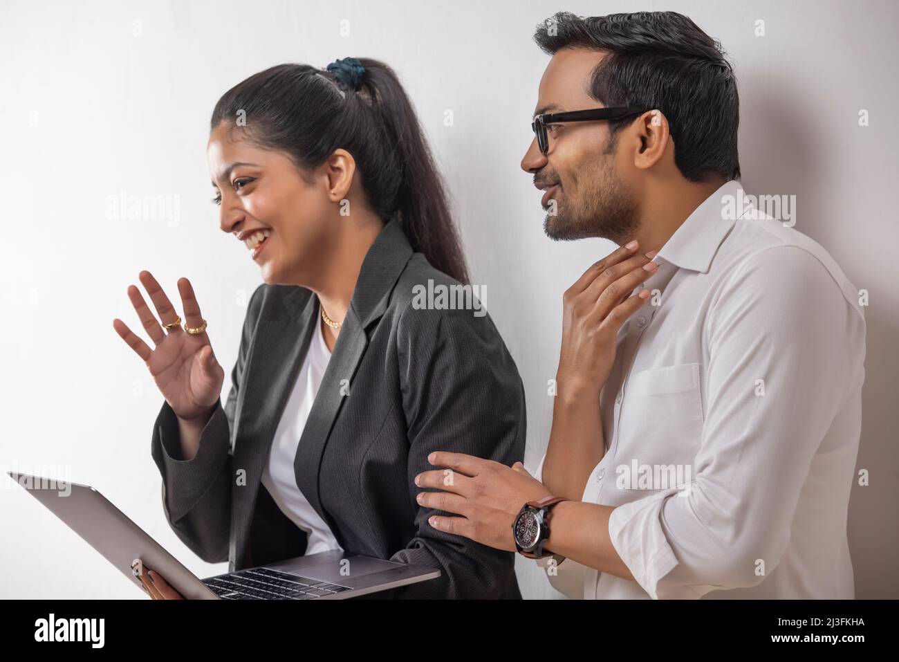 Office colleagues smiling together while doing office work using laptop ...