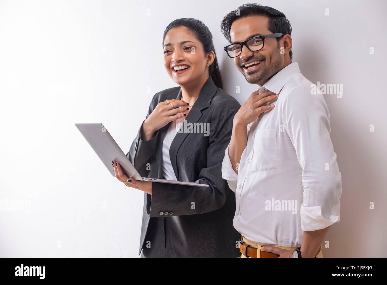 Office colleagues smiling together while doing office work using laptop ...