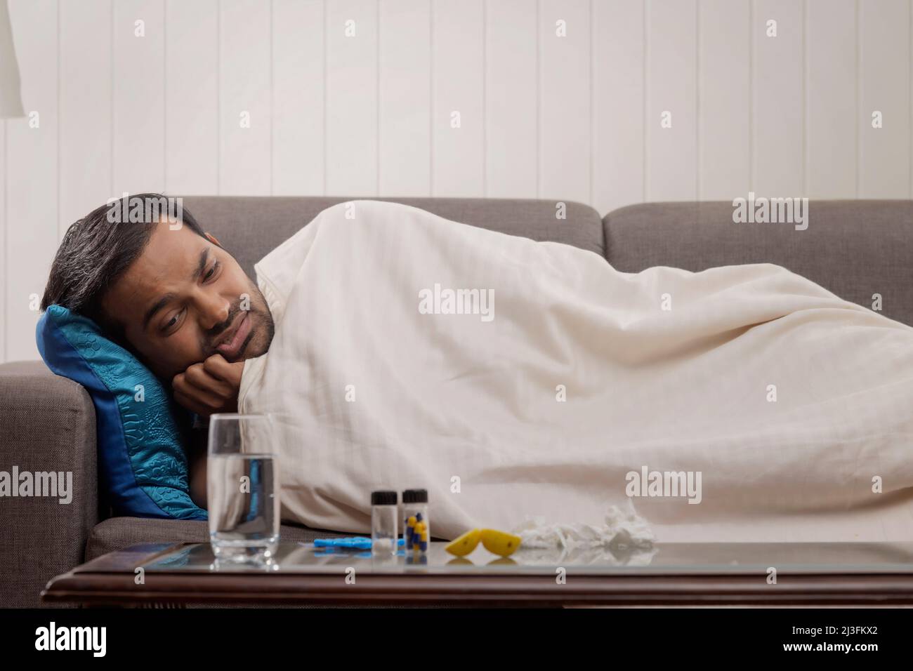 A sick young man lying on sofa while suffering from fever Stock Photo - Alamy