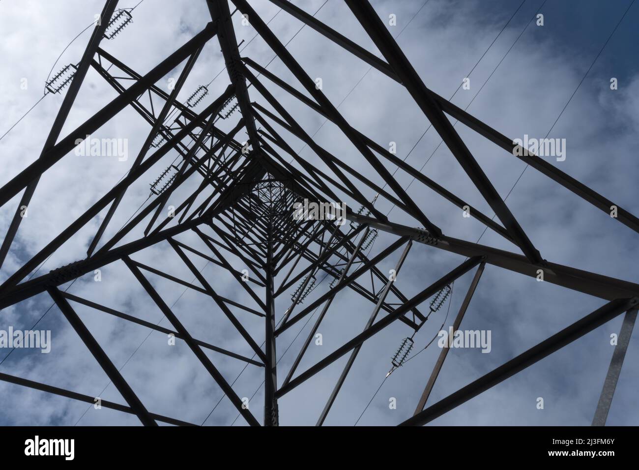 Looking upward in the center of a large tall massive high voltage pylon ...