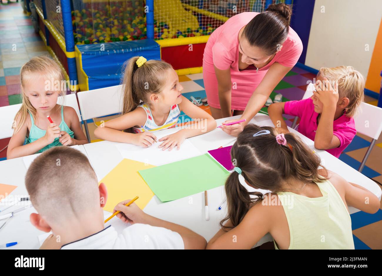 Group of kids drawing on lesson with help of teacher Stock Photo - Alamy