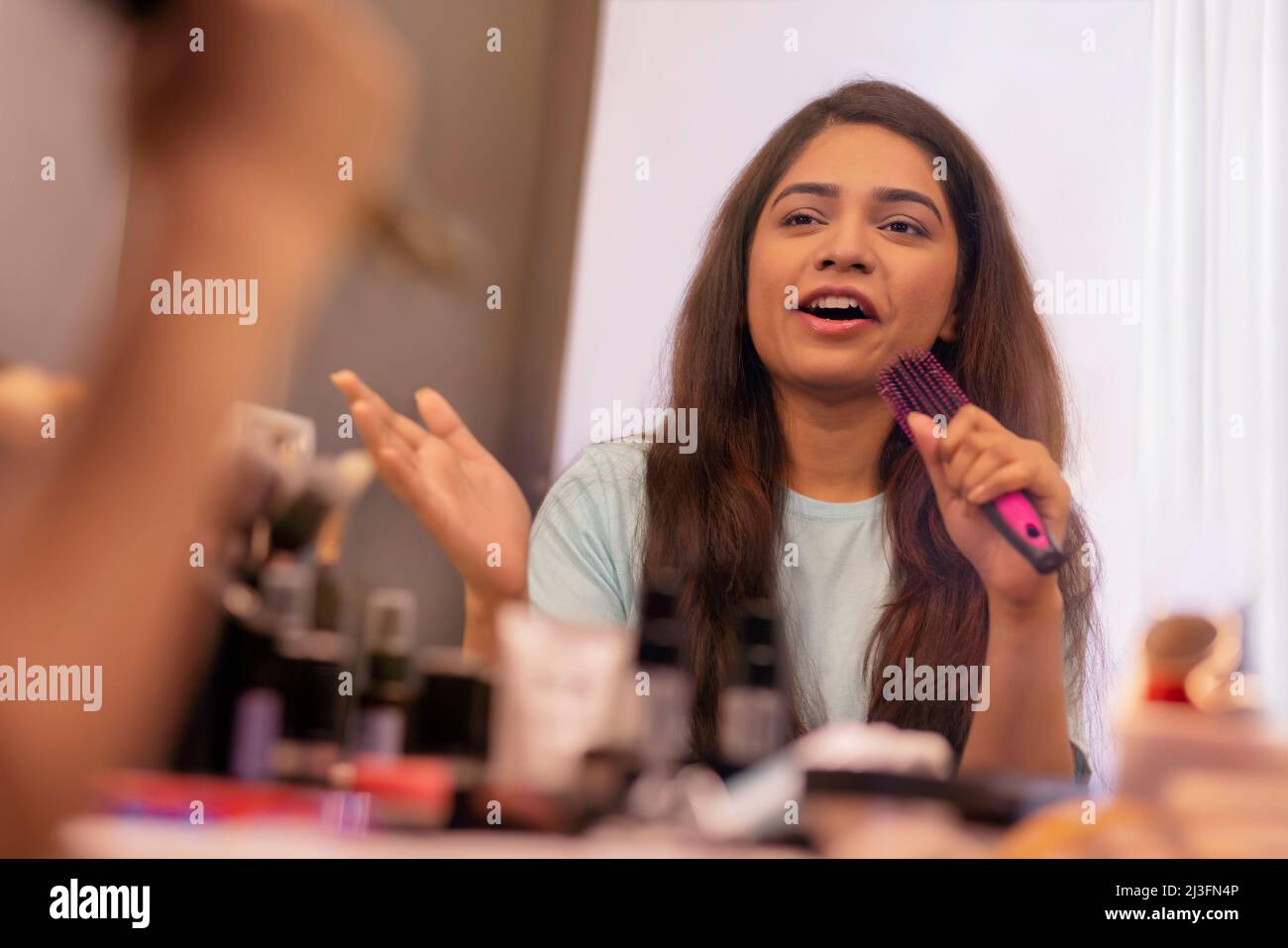 Young Woman Holding Hairbrush While Singing at makeup room Stock Photo ...