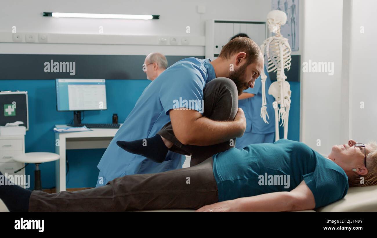 Physiotherapist assisting elder patient with physical injury, giving ...