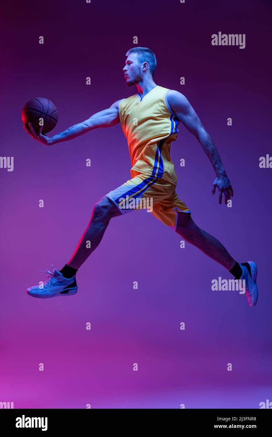 Studio shot of muscled man, basketball player training with ball ...