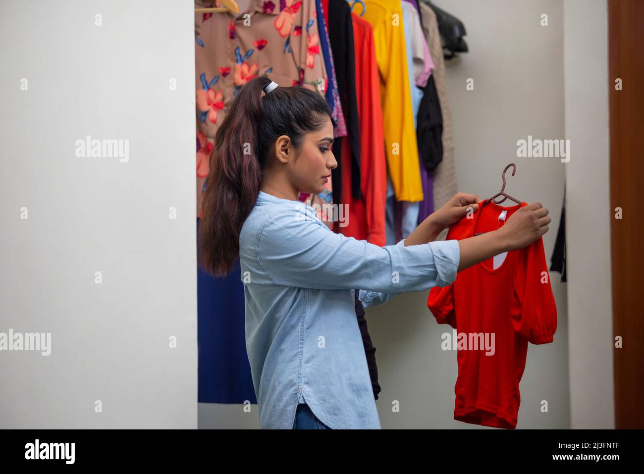 Young woman selecting dress at shopping mall Stock Photo - Alamy