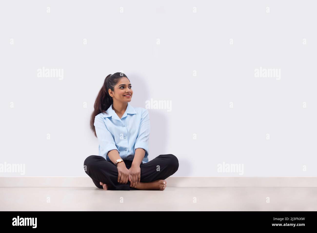 Young business woman in formal outfit sitting on floor and looking ...