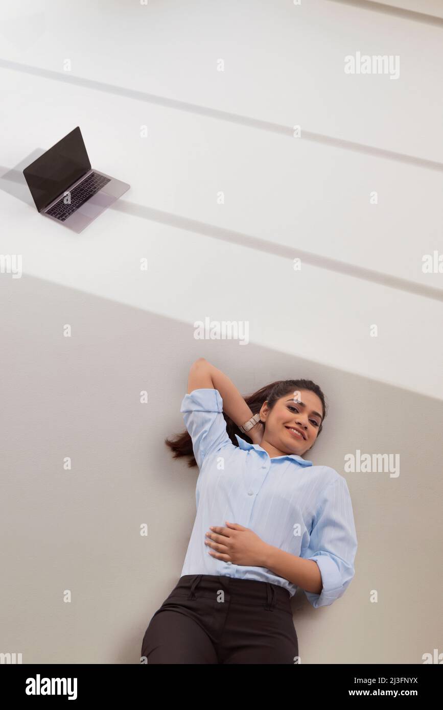 Young business woman in formal outfit lying on floor with hand behind ...