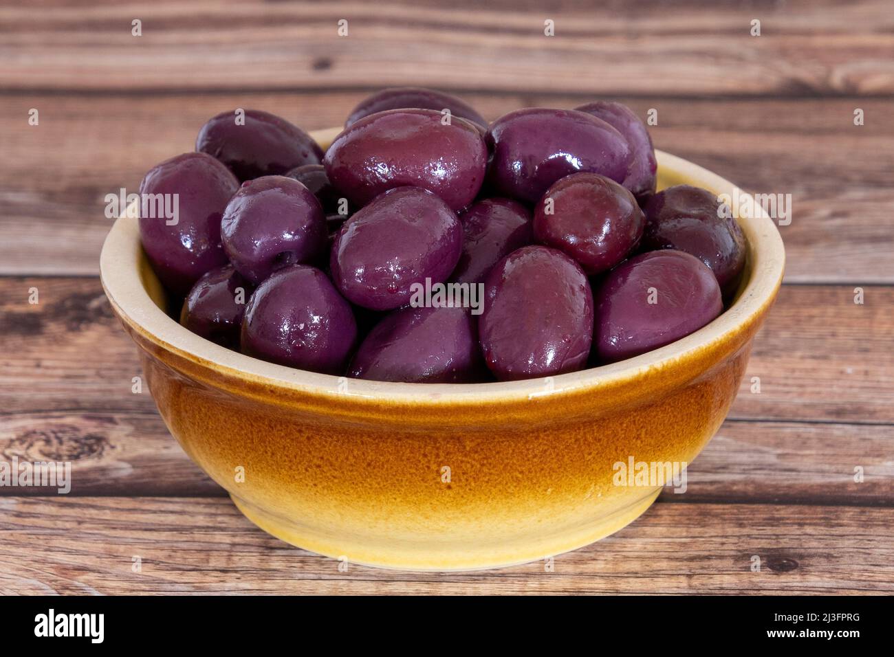 purple olives in a bowl on a wooden board Stock Photo - Alamy