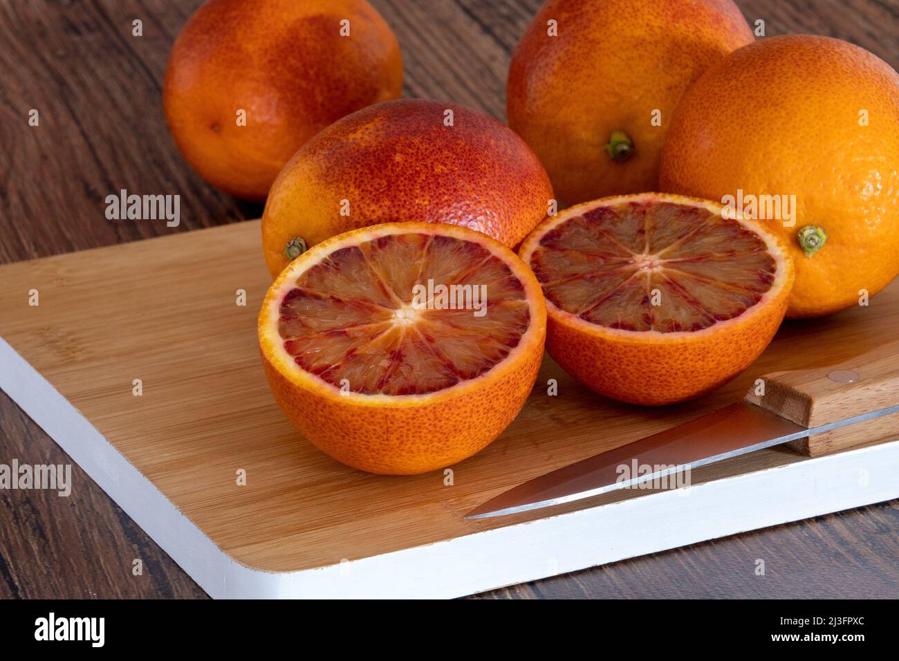 cut blood oranges isolated on a wooden board with a knife Stock Photo ...