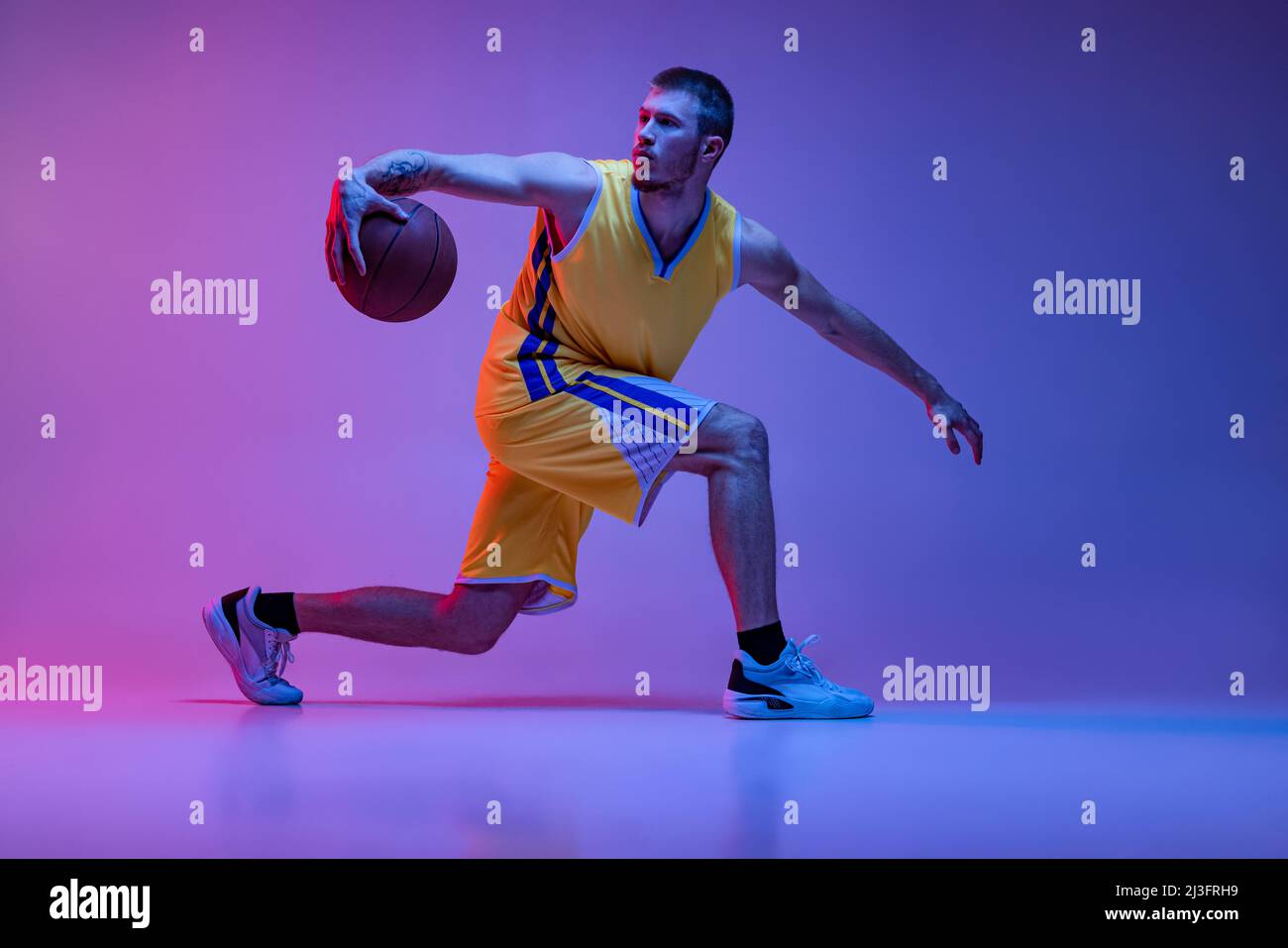 Studio shot of muscled man, basketball player training with ball ...