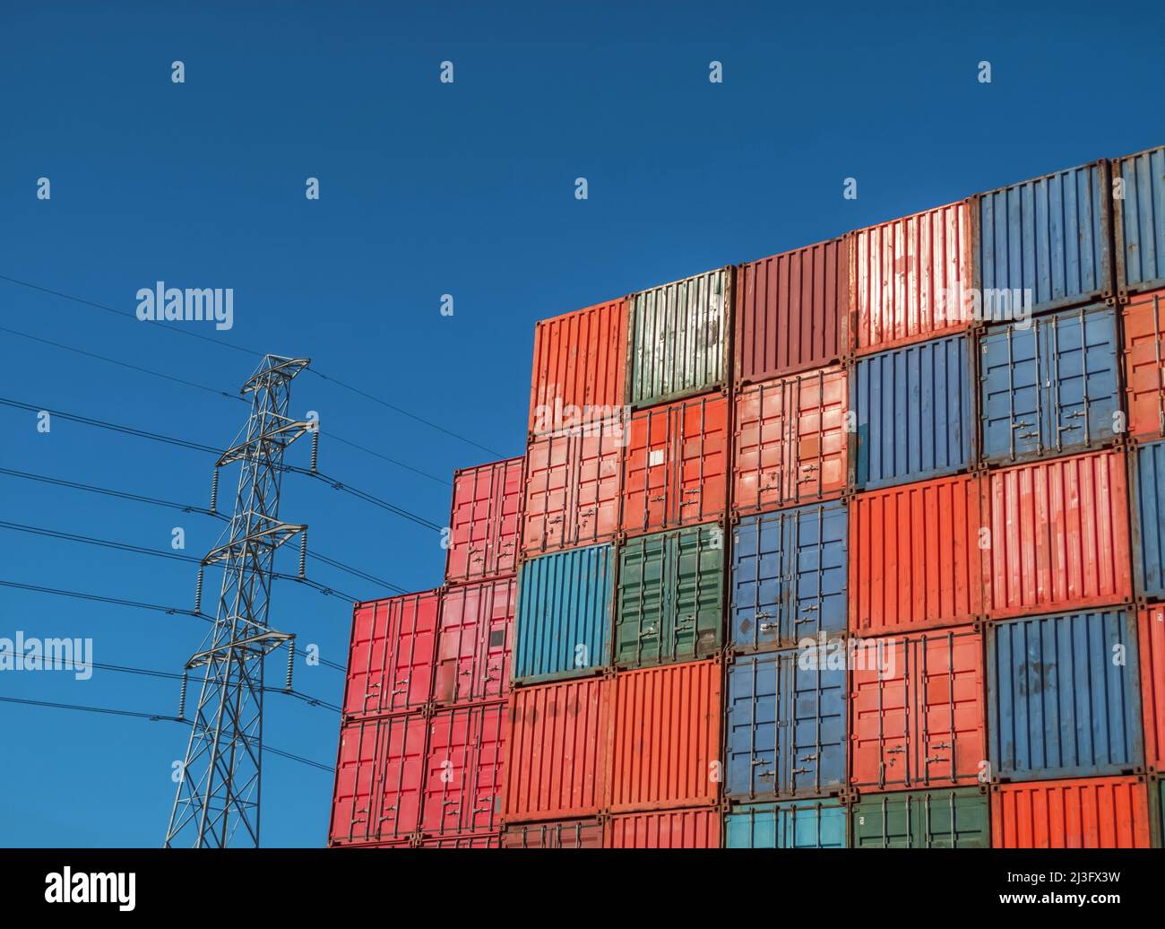 Stack of shipping containers with electricity pylon in distance against ...