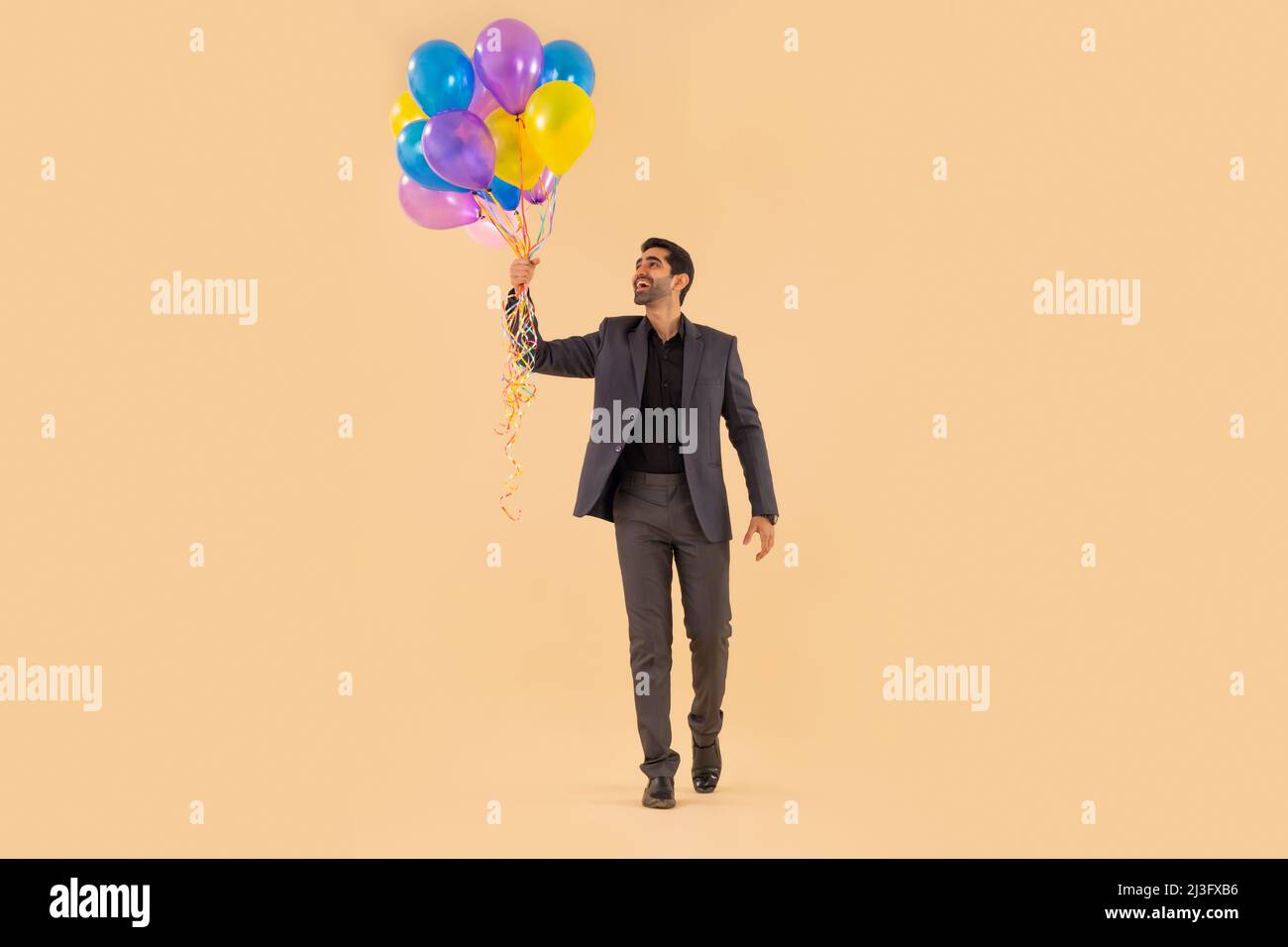Happy businessman in formal outfit holding a bunch of balloons Stock ...