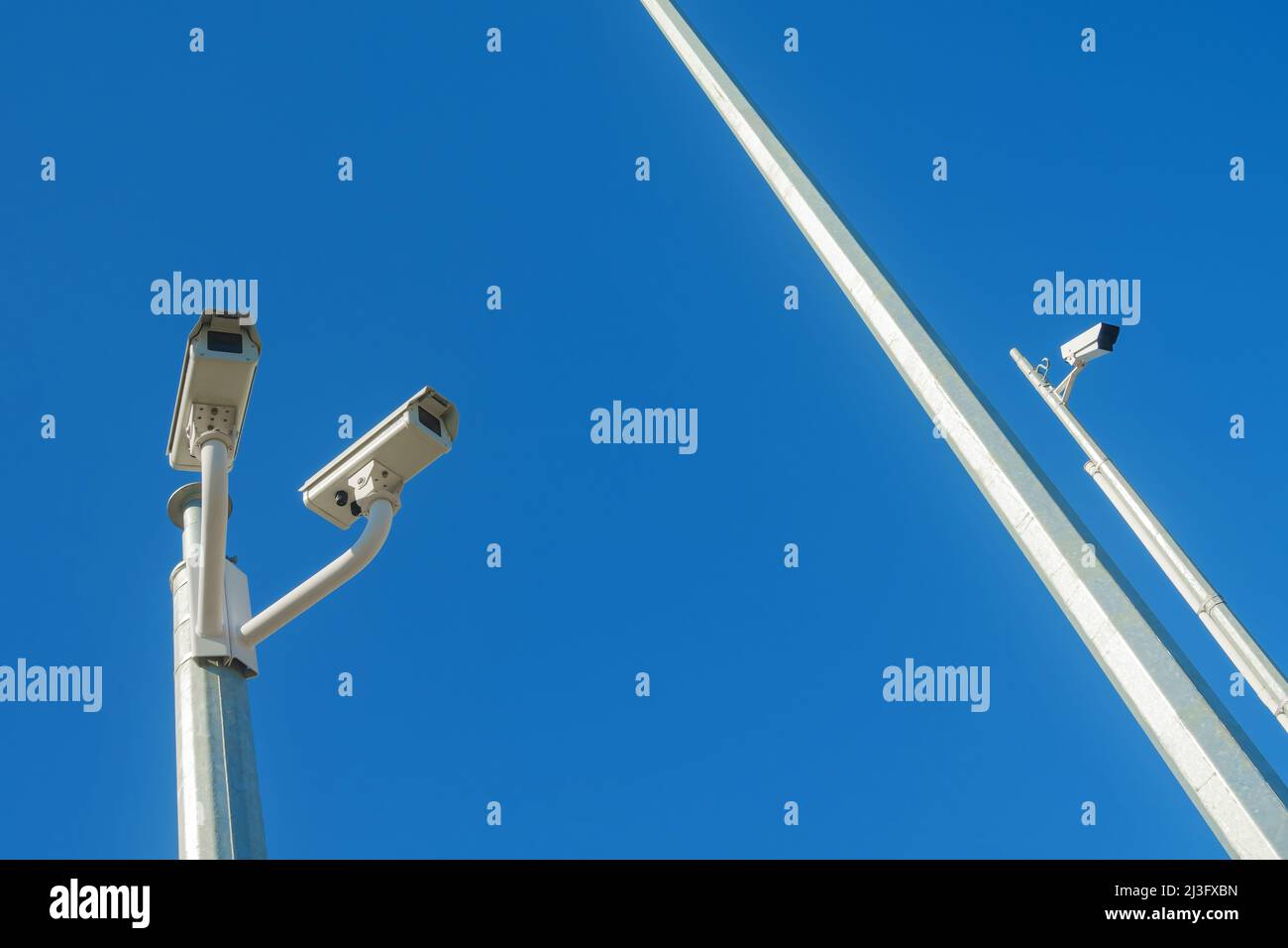 Closed circuit television cameras isolated against a clear blue sky ...