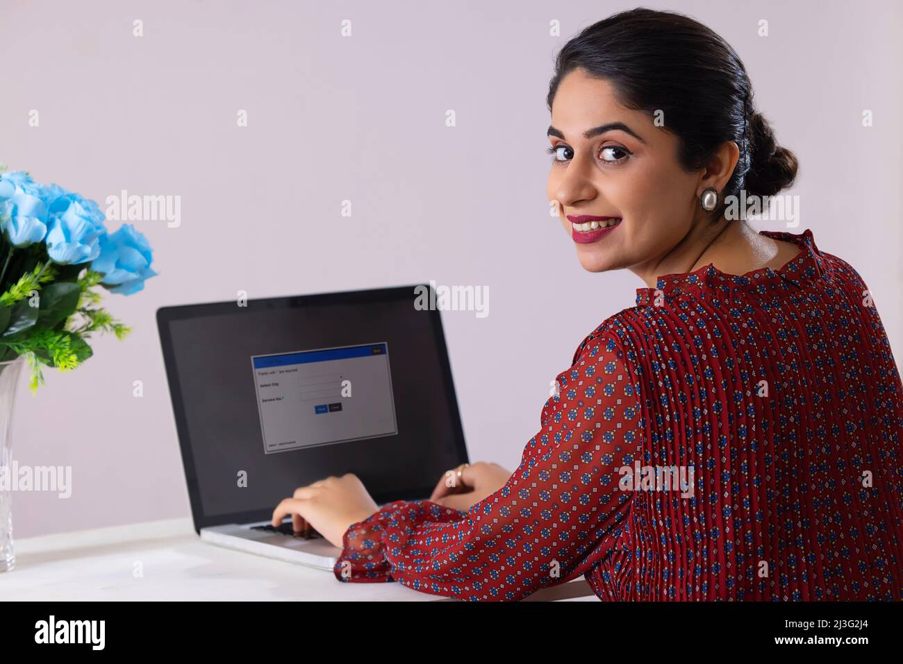 Portrait of a working woman looking back at camera while working at her ...