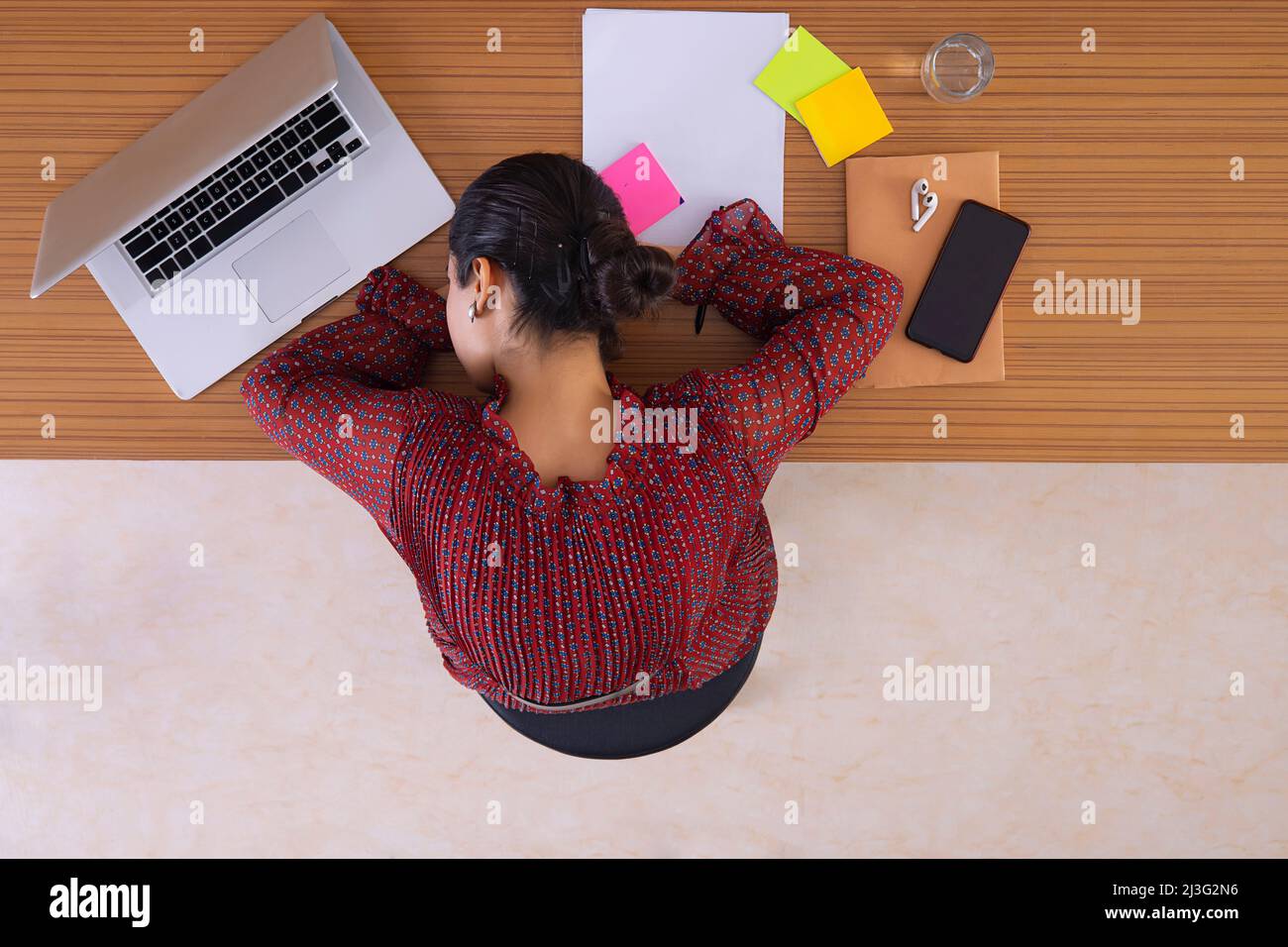 Overhead view of a working woman leaning her head on desk in office ...