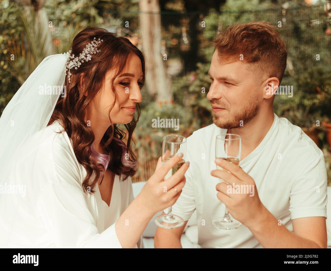 Stylish, smiling groom and cute blonde bride with curly hair in a white ...