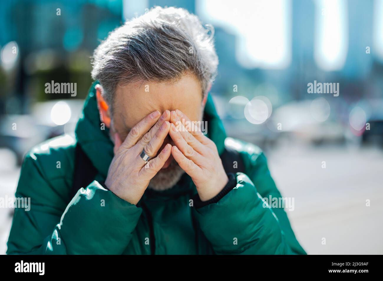 Man standing with hands on head, having a headache Stock Photo - Alamy