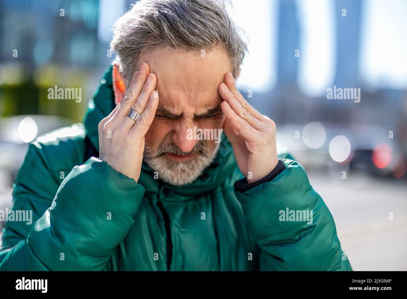 Man standing with hands on head, having a headache Stock Photo - Alamy
