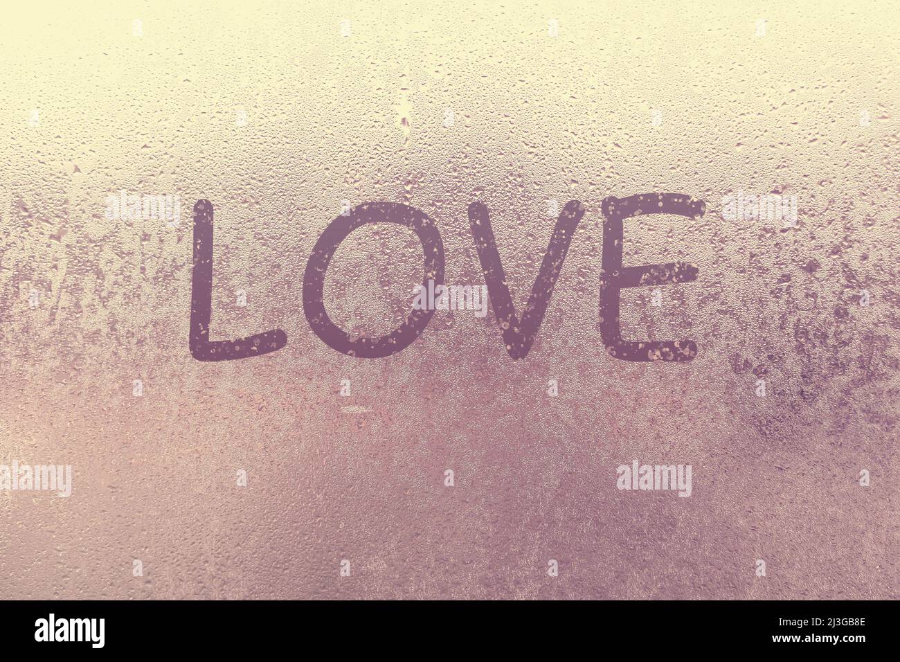 Word Love and shape of heart are drawn with a finger on fogged window ...