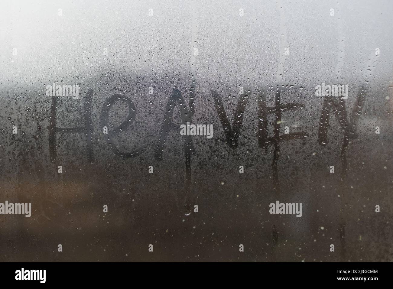 Word Heaven, Handwritten inscription on the glass. Water drops on the ...