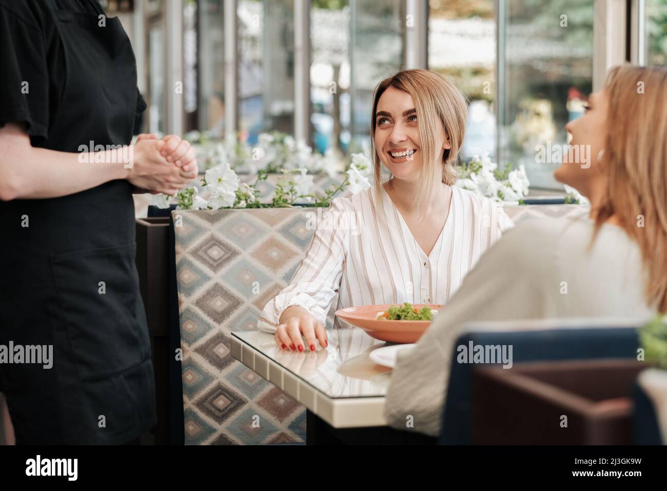 Two Happy And Cheerful Women Having Lunch Time Making Order To Female Waiter In The Restaurant