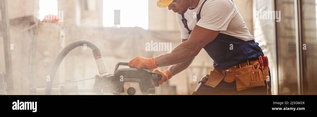Male builder using wood cutting circular saw machine in workshop Stock ...