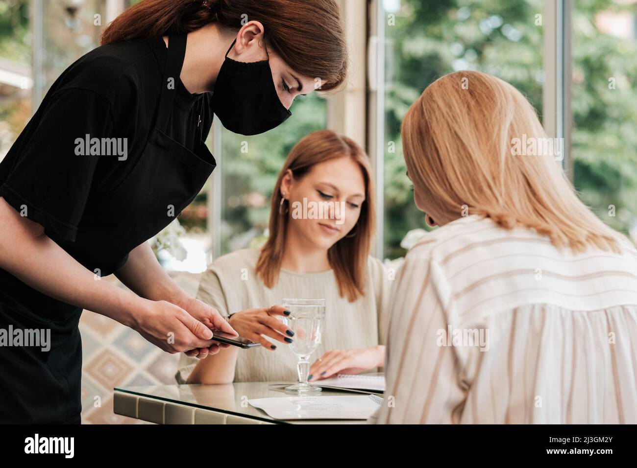 Two Women Sitting in Restaurant and Making Order, Female Waiter Wearing ...