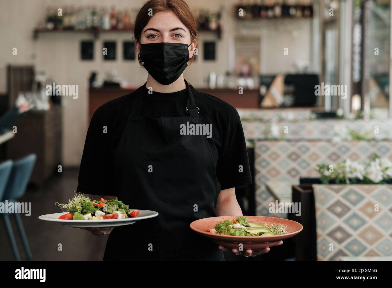 Portrait of Young Female Waiter Wearing Protection Mask that Holding ...