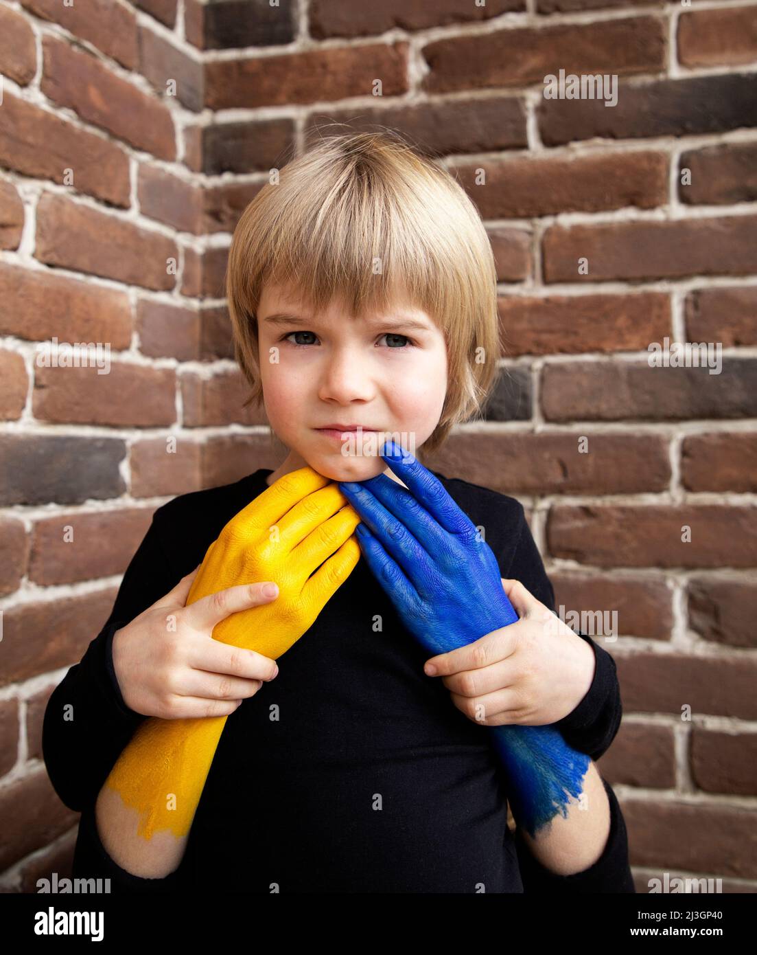 Children against war. female hands, painted in yellow and blue, embrace ...