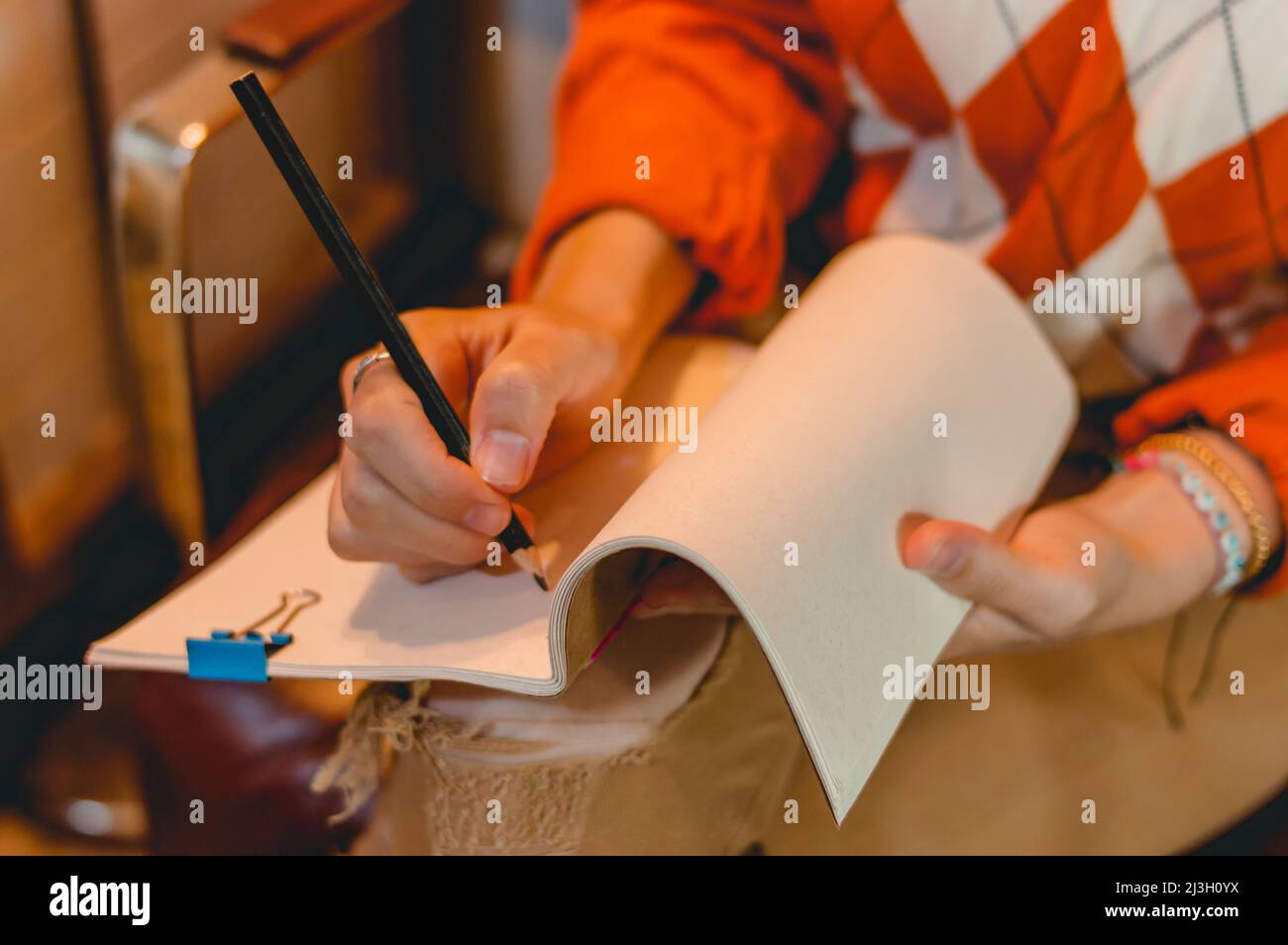 unrecognizable caucasian woman sitting writing with a black pencil on a ...
