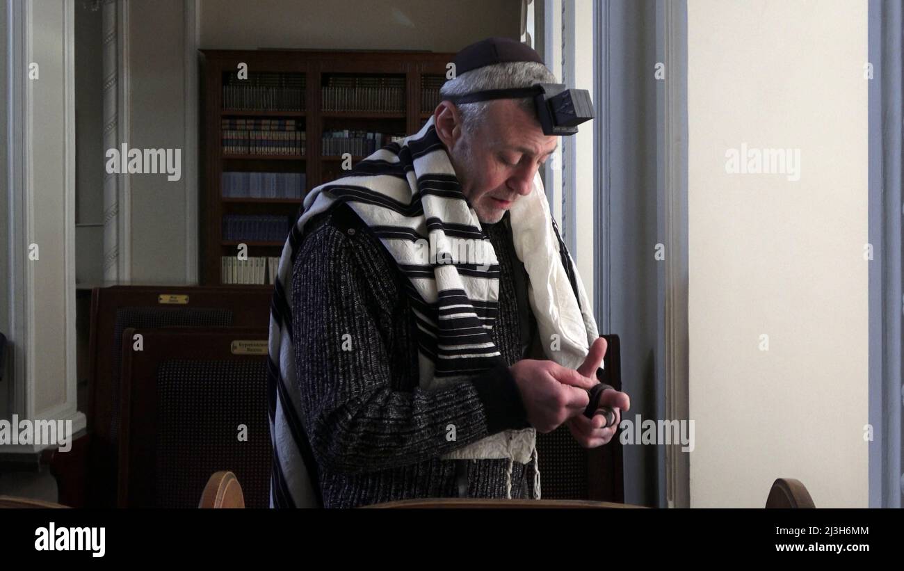 A Ukrainian Jew wraps black leather strap of Tefilin phylacteries ...