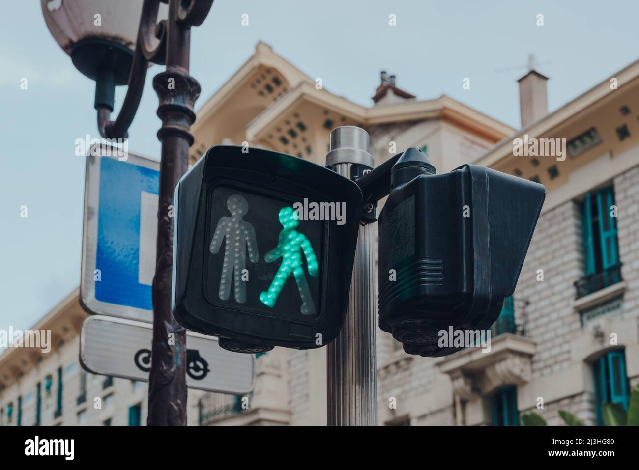 Low angle view of a green pedestrian traffic light on a street in Nice ...