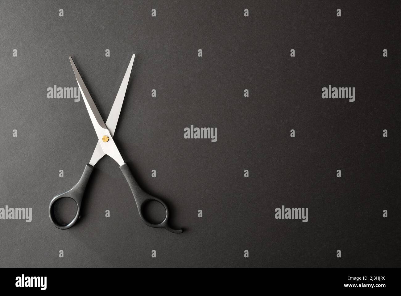 Basic conceptual hairdressing background with scissors on a black ...