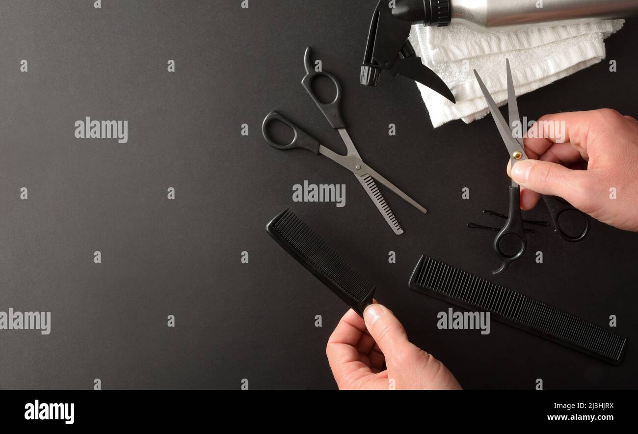 Hairdresser's hands picking up hairdressing tools on black table full ...