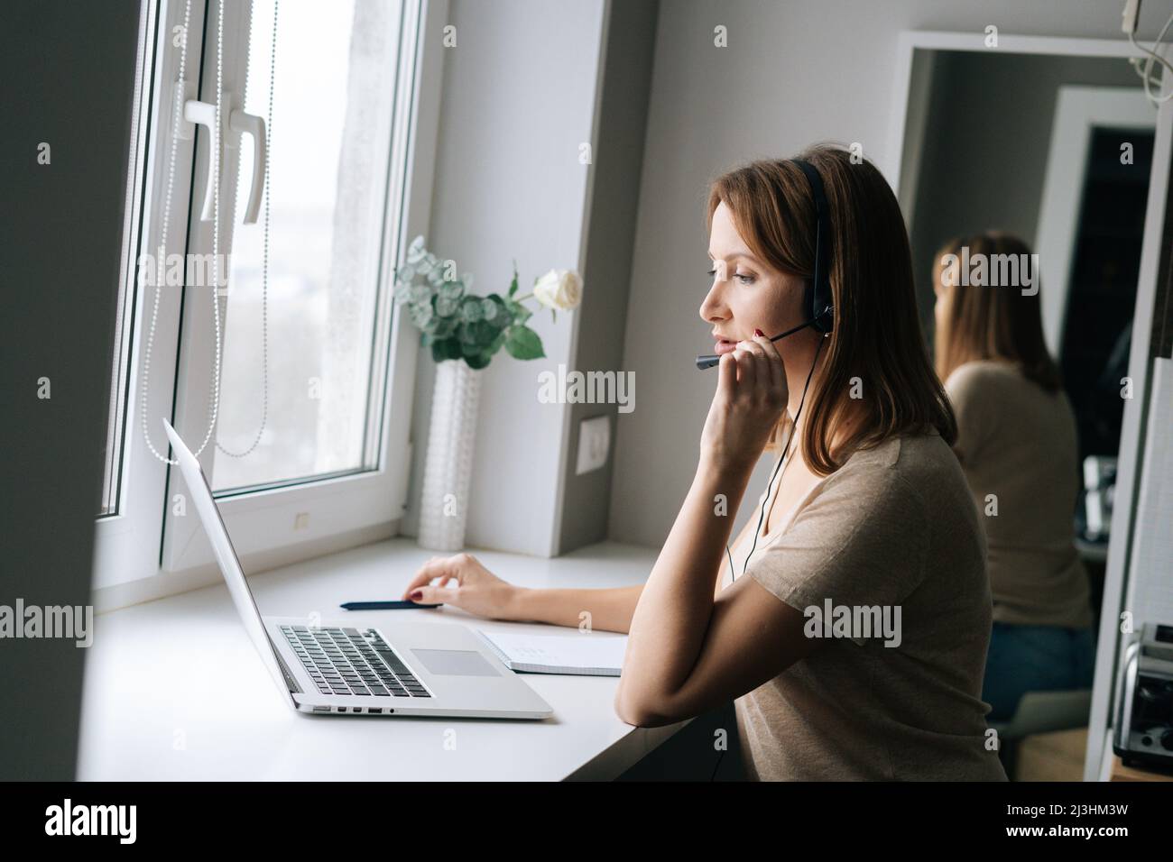 Side view of focused female operator talking using headset and ...